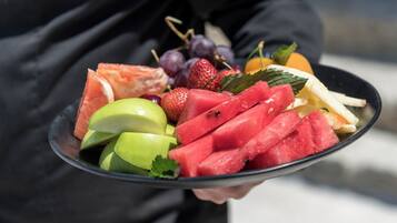 Uma pessoa segurando uma tigela com frutas variadas, incluindo melancia, morangos, uvas e maçãs.