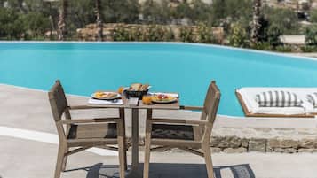Mesa de jantar com cadeiras de vime e vista para uma piscina.
