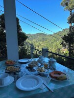 Uma mesa posta para o café da manhã com vista para uma paisagem montanhosa.