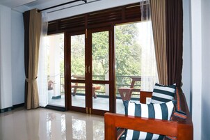 Quarto com porta de vidro deslizante que dá para um pátio ao ar livre com mesa e cadeiras de madeira.