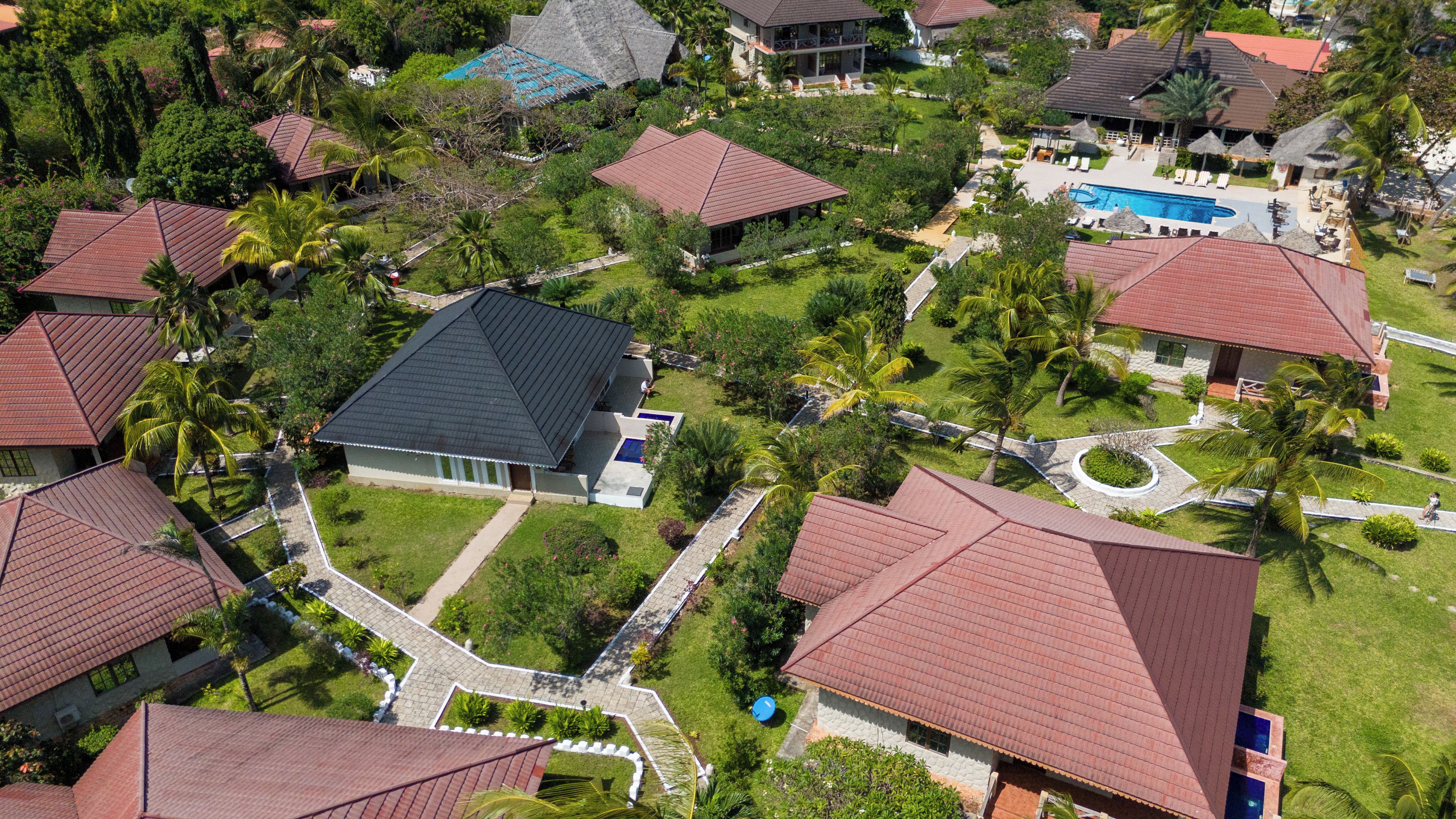 Vista aérea de um resort com vários edifícios, piscina e vegetação exuberante.