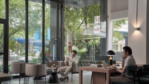 Espaço interior moderno com grandes janelas, áreas de estar e uma mesa com um laptop.
