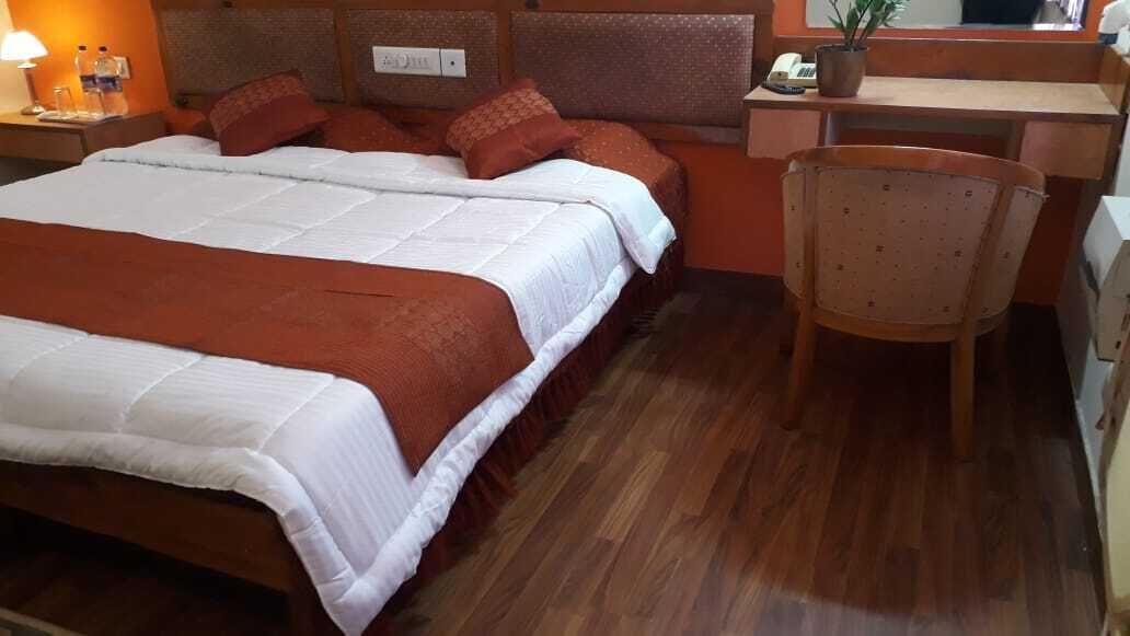 Quarto de hotel com duas camas, uma escrivaninha e uma cadeira.