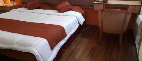 Quarto de hotel com duas camas, uma escrivaninha e uma cadeira.