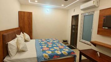 Quarto com cama de madeira, ventilador de teto, ar-condicionado, televisão e mesa de cabeceira.
