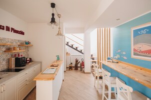 Cozinha moderna com ilha de madeira, armários brancos e uma parede azul de destaque.