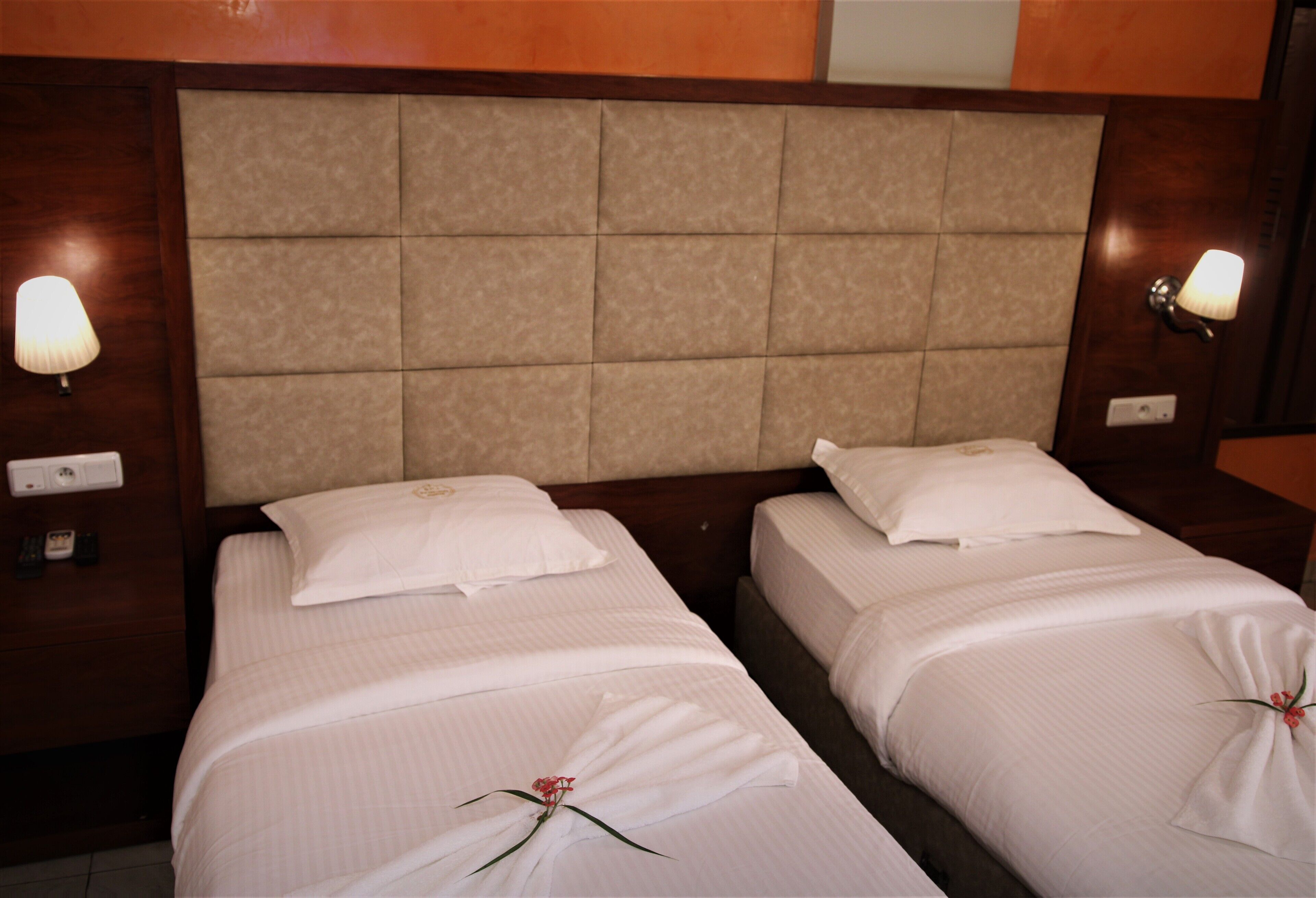 Quarto de hotel com duas camas, cada uma com cabeceira, abajures e uma pequena mesa com telefone.