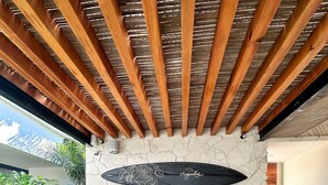 Uma área de pátio com móveis de vime, parede de pedra e uma prancha de surf.