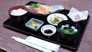 Uma bandeja com diversos pratos japoneses, incluindo arroz, sashimi e sopa.