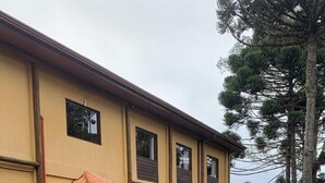 Um edifício com telhado de telhas, um lago com uma fonte e uma pérgula de madeira.