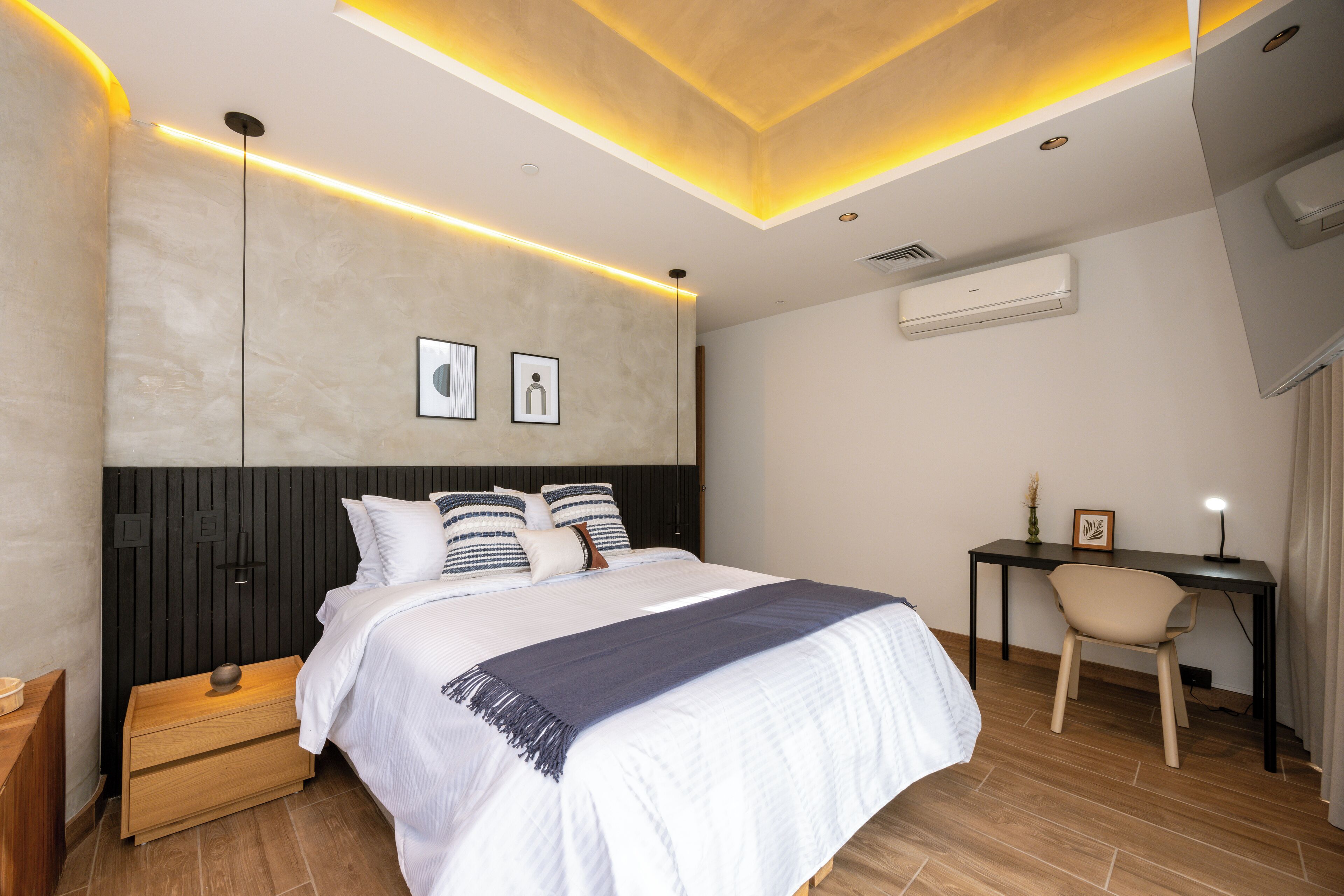 Quarto moderno com cama, mesas de cabeceira, escrivaninha e cadeira.