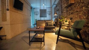 Uma sala de estar aconchegante com sofá, poltrona, mesa de centro e televisão na parede.