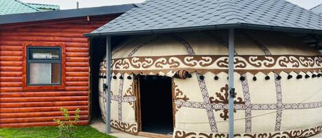 Uma cabana de madeira com uma entrada de padrão característico e um espaço de pátio com azulejos.