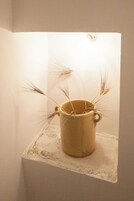 Uma caneca de cerâmica com espigas de trigo numa prateleira.