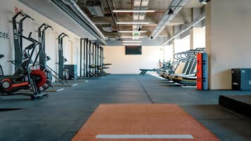 Uma academia com diversos equipamentos de exercício, incluindo esteiras e máquinas de peso, dispostos em fileiras.
