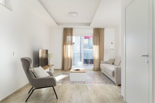 Uma sala de estar moderna com sofá, poltrona, televisão e tapete estampado.