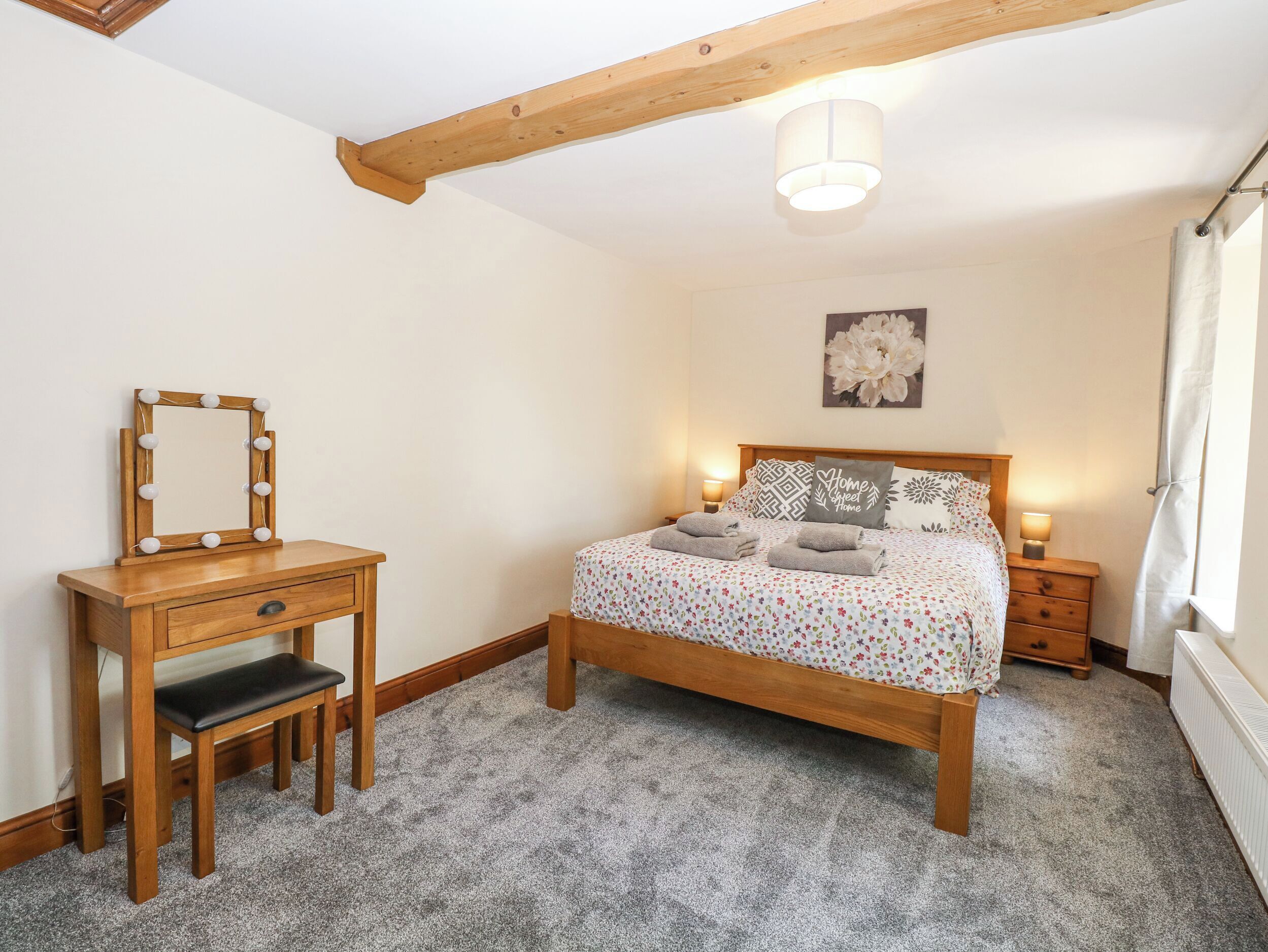 Quarto com cama de madeira, toucador com espelho e pequena escrivaninha.