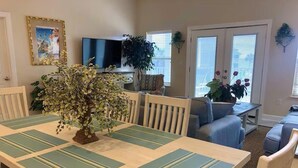 Uma área de refeições com uma mesa de madeira, jogos americanos verdes e uma planta em vaso.