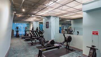 Uma academia com equipamentos de exercícios, um aviso de extintor de incêndio e um espelho na parede.