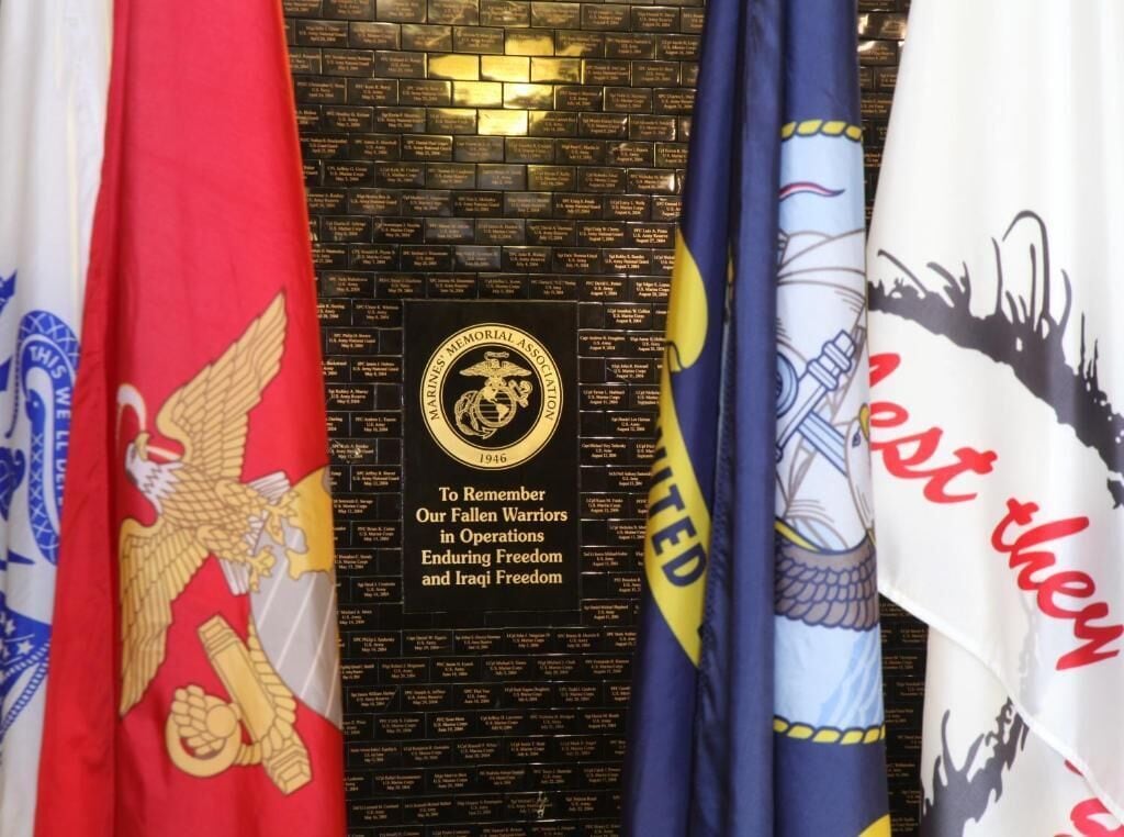 Uma parede com uma placa comemorativa e bandeiras.