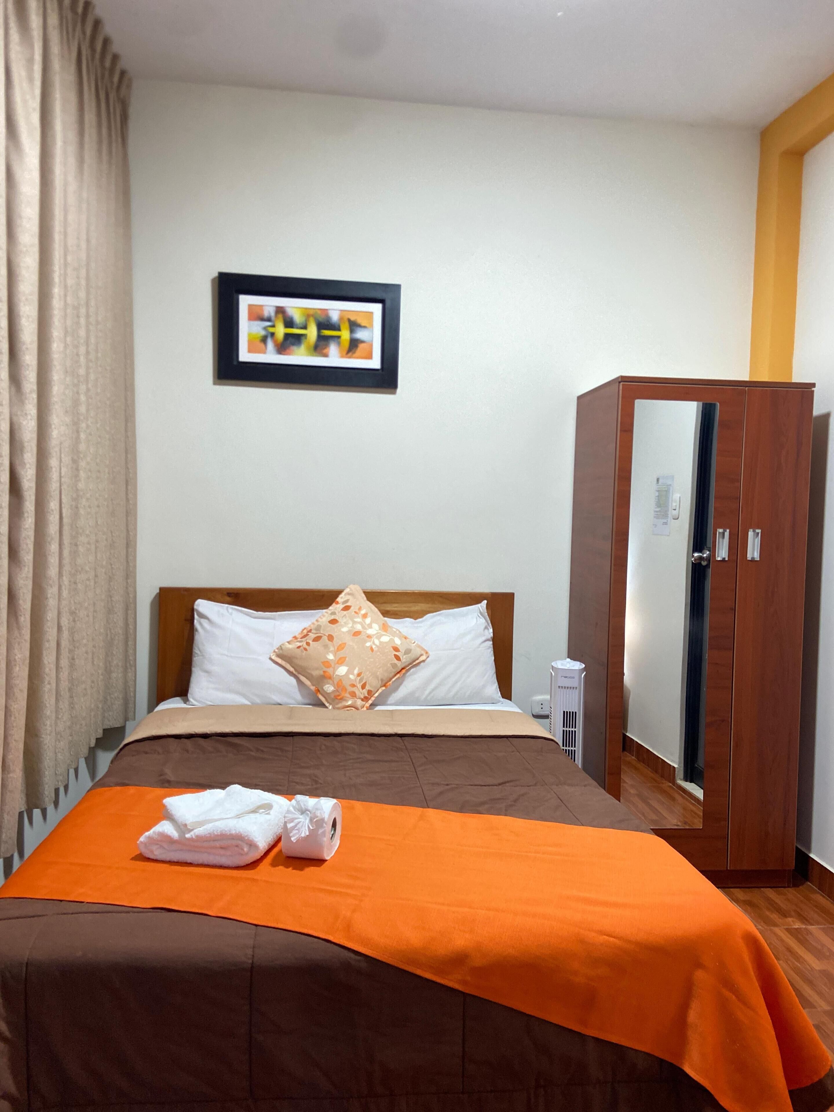 Quarto de hotel com cama, guarda-roupa e um quadro na parede.