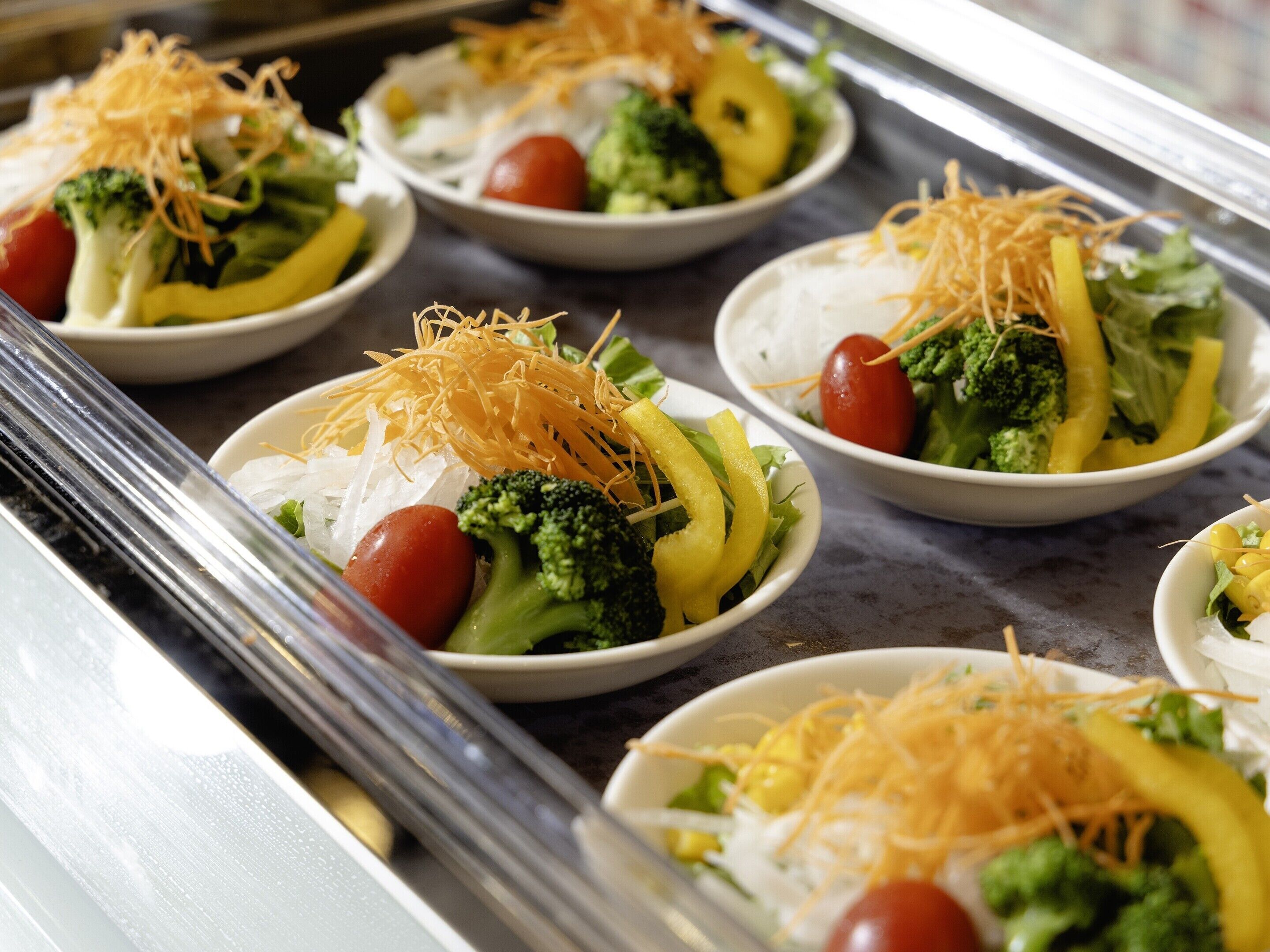 Buffet com diversos pratos, incluindo saladas, legumes e queijo ralado.