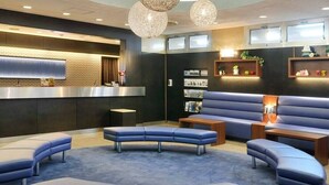 Um lobby moderno com balcão de recepção, área de estar e iluminação decorativa.