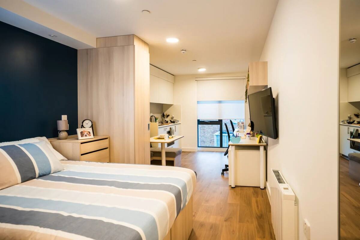 Quarto moderno com uma cama grande, uma escrivaninha e uma televisão.
