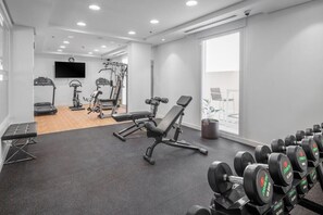 Uma academia com equipamentos de ginástica, um banco e halteres.