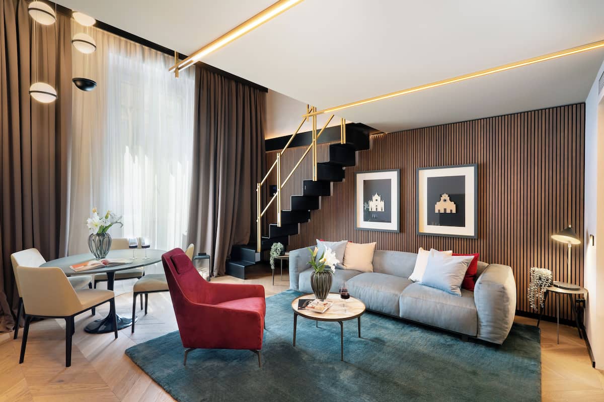 Uma sala de estar moderna com sofá, poltrona vermelha, mesa de centro e escada com guarda-corrimão preto.