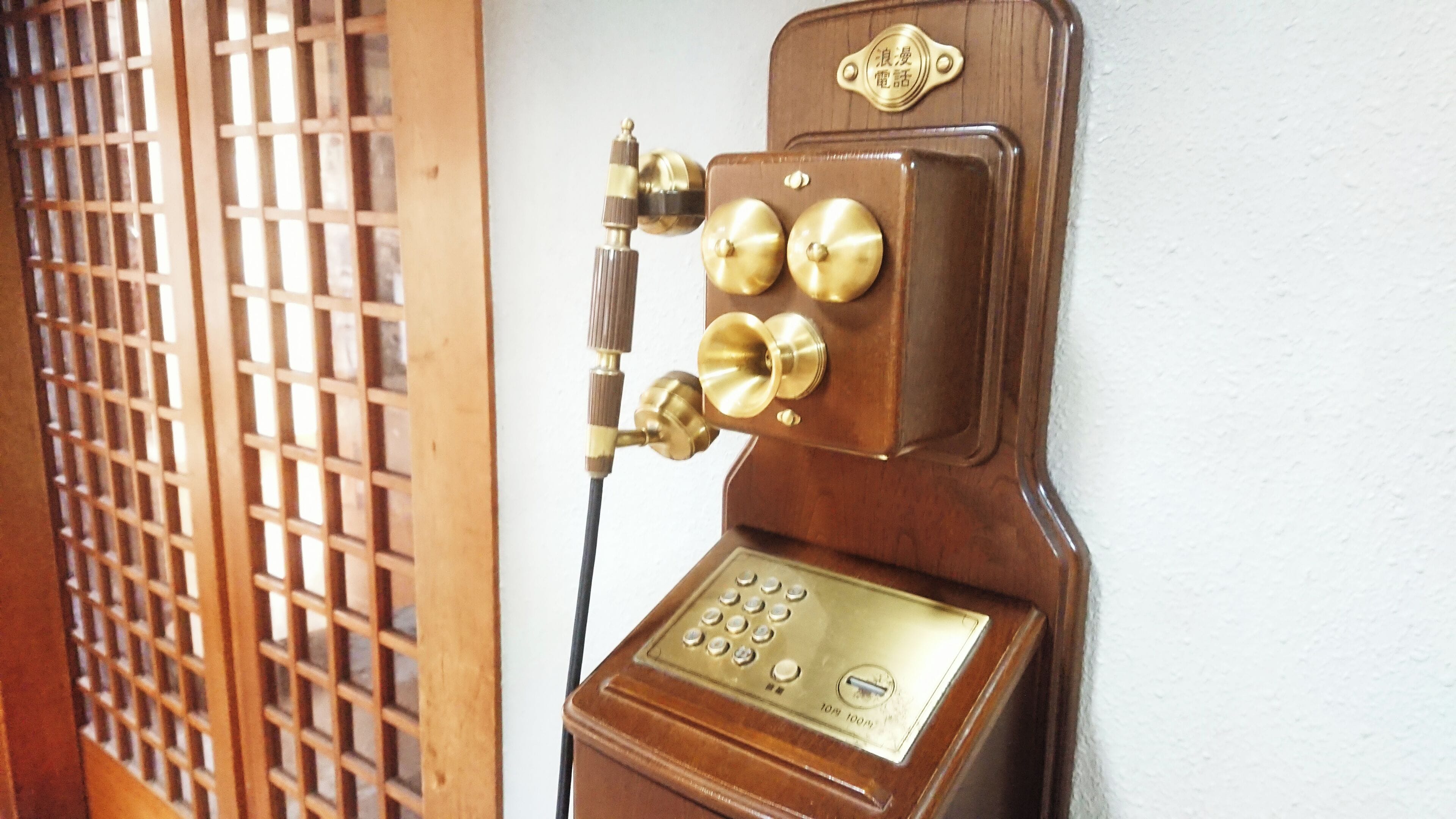 Telefone antigo fixado numa parede de madeira.