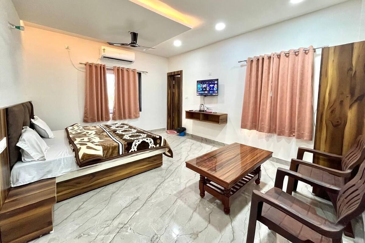 Quarto de hotel moderno com cama, uma mesa de madeira e duas cadeiras.