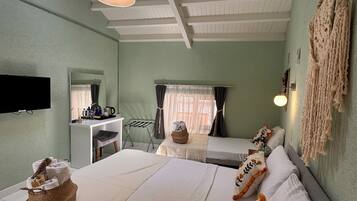 Quarto de hotel com uma cama grande, uma escrivaninha pequena, um espelho e uma janela com cortinas.
