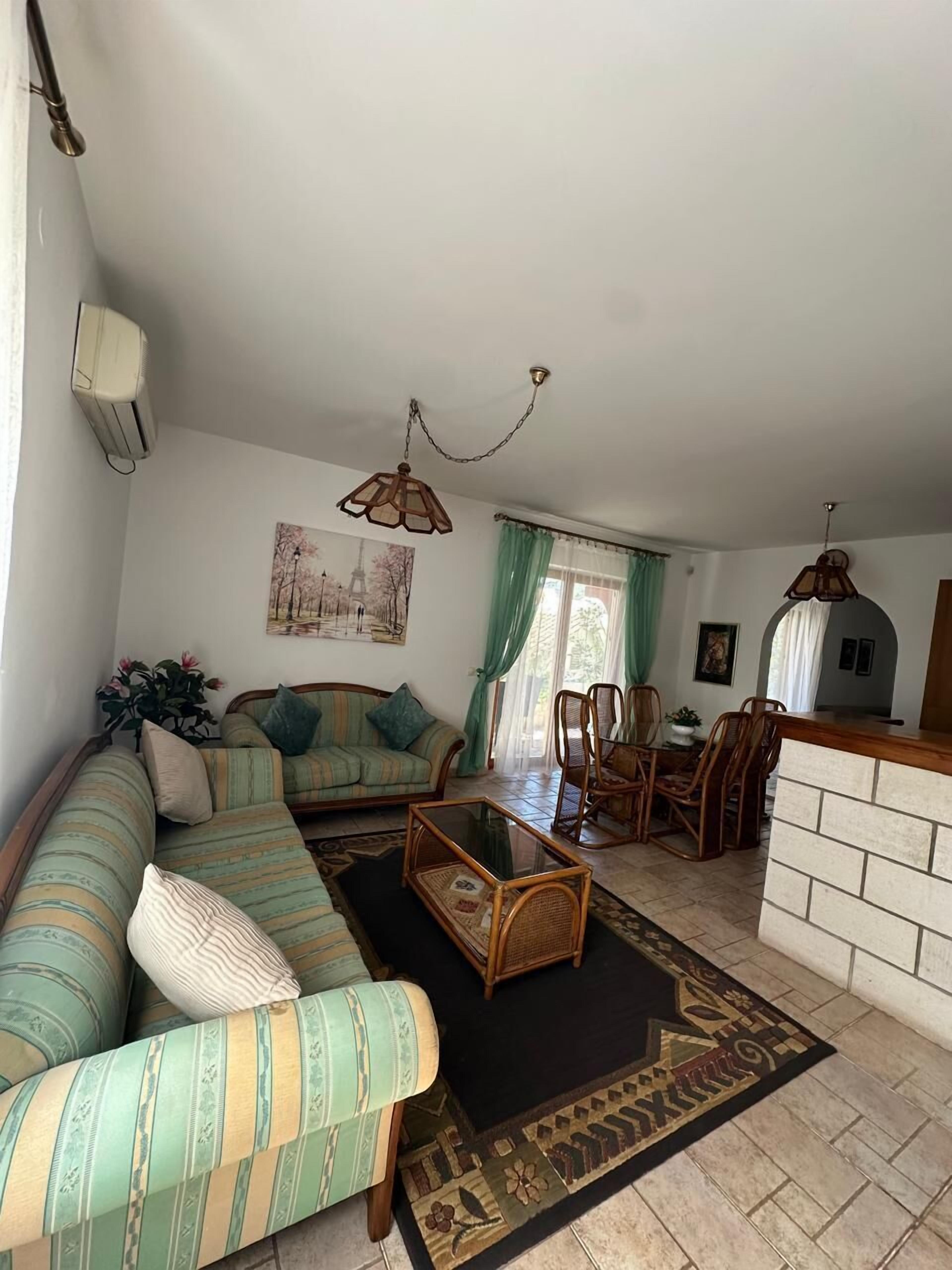 Uma sala de estar com sofá, cadeiras, uma mesa de centro e um espaço para refeições.
