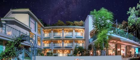 Hotel com placa visível, várias varandas e céu noturno estrelado.