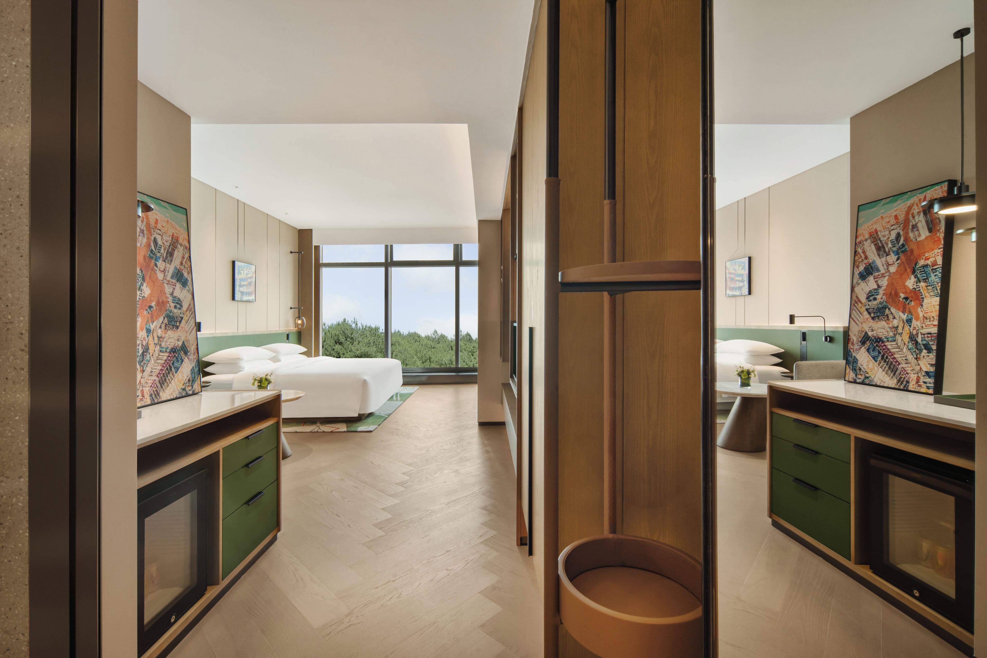 Quarto de hotel moderno com uma cama grande, uma escrivaninha e vista para o exterior.