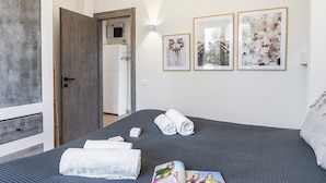 Quarto com cama, toalhas e quadros na parede.