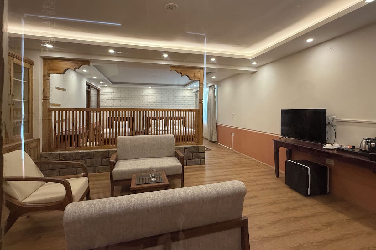 Uma sala de estar moderna com televisão, área de estar e escada que leva a uma varanda.