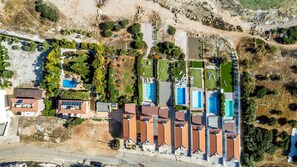 Vista aérea de um bairro residencial com várias casas, piscina e uma rua.
