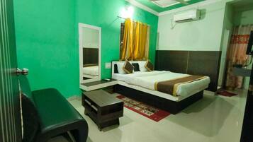 Quarto de hotel com cama, um banco, um espelho e ar condicionado.