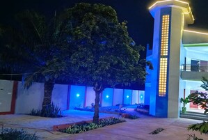 Um edifício moderno com uma luminária vertical destacada e uma árvore em primeiro plano.