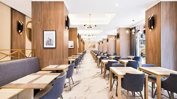 Um restaurante moderno com painéis de madeira, piso de mármore e um balcão comprido com cadeiras azuis.