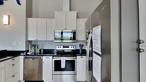 Uma cozinha moderna com armários brancos, eletrodomésticos de aço inoxidável e piso de madeira.