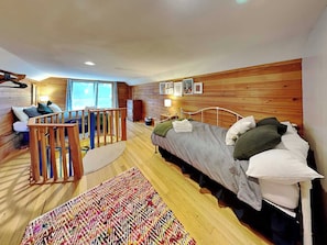 Quarto com cama, escrivaninha, cadeira e janela.