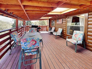 Um deck coberto com mesa e cadeiras, uma bandeira americana e vista para o exterior.