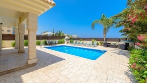 Piscina com espreguiçadeiras e uma estrutura de pérgola.