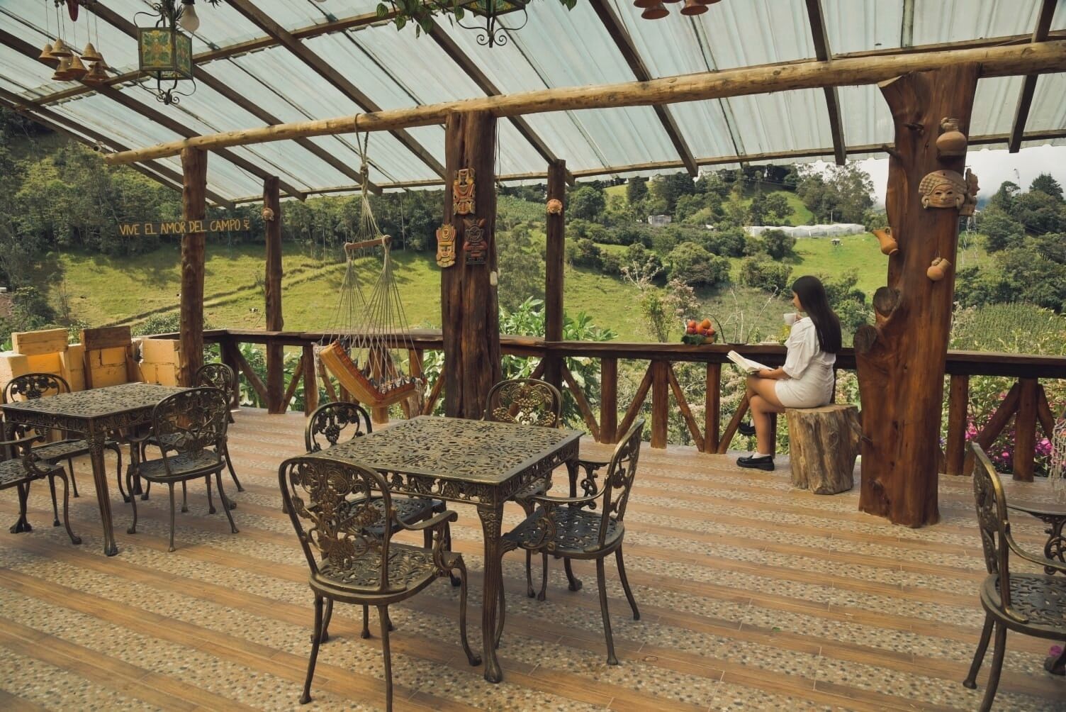 Um pátio externo com móveis de madeira rústica e vista para uma paisagem exuberante.