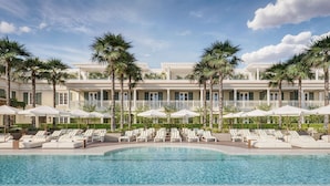 Um hotel com piscina, espreguiçadeiras, palmeiras e guarda-sóis.