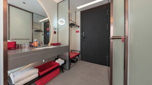 Um banheiro moderno com um espelho grande, um lavatório com porta-toalhas vermelho e uma porta preta.