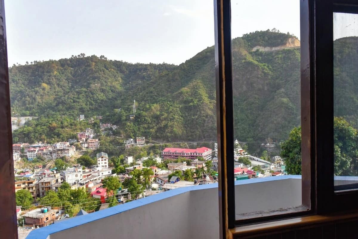 Vista da janela com a paisagem de uma cidade, edifícios e colinas ao fundo.